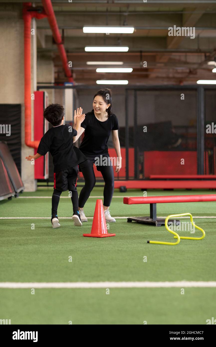 Cute boy having exercise class with coach in gym Stock Photo - Alamy