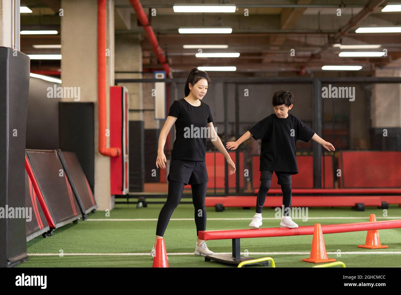 Cute boy having exercise class with coach in gym Stock Photo - Alamy