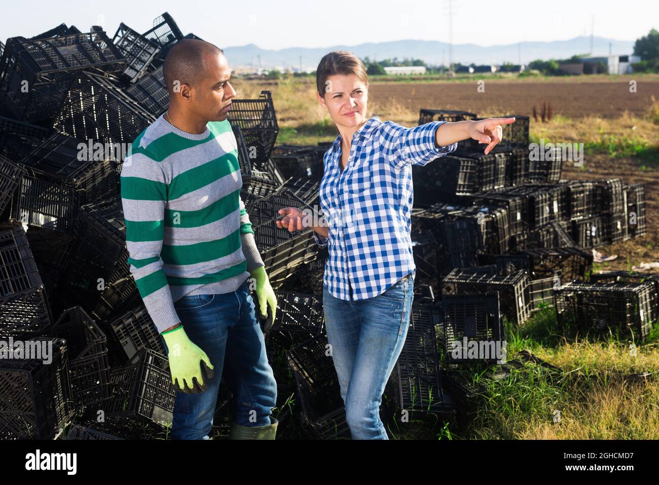 Farm owner gives instructions to the hired worker on the farm field ...