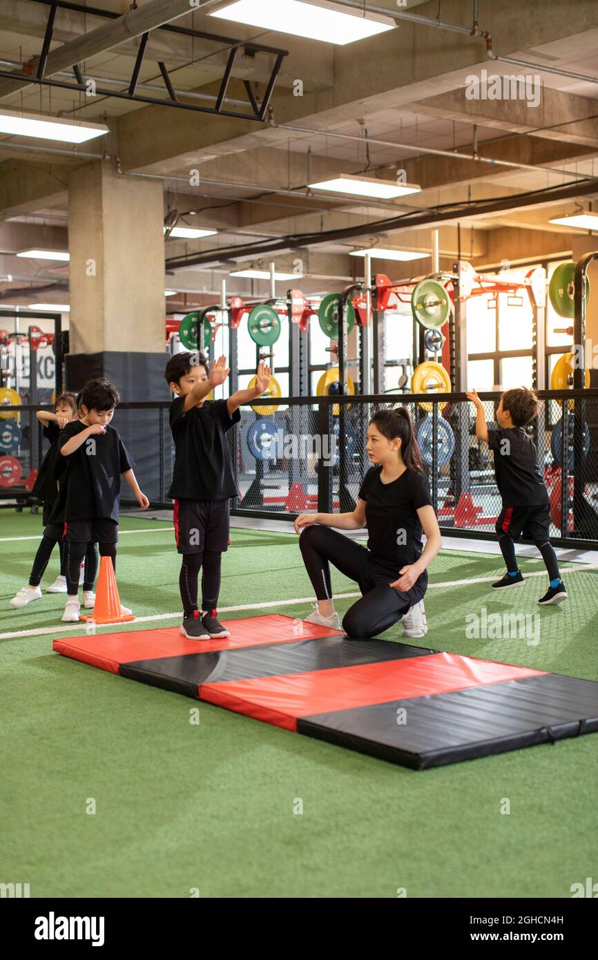 Active children having exercise class with their coach in gym Stock ...