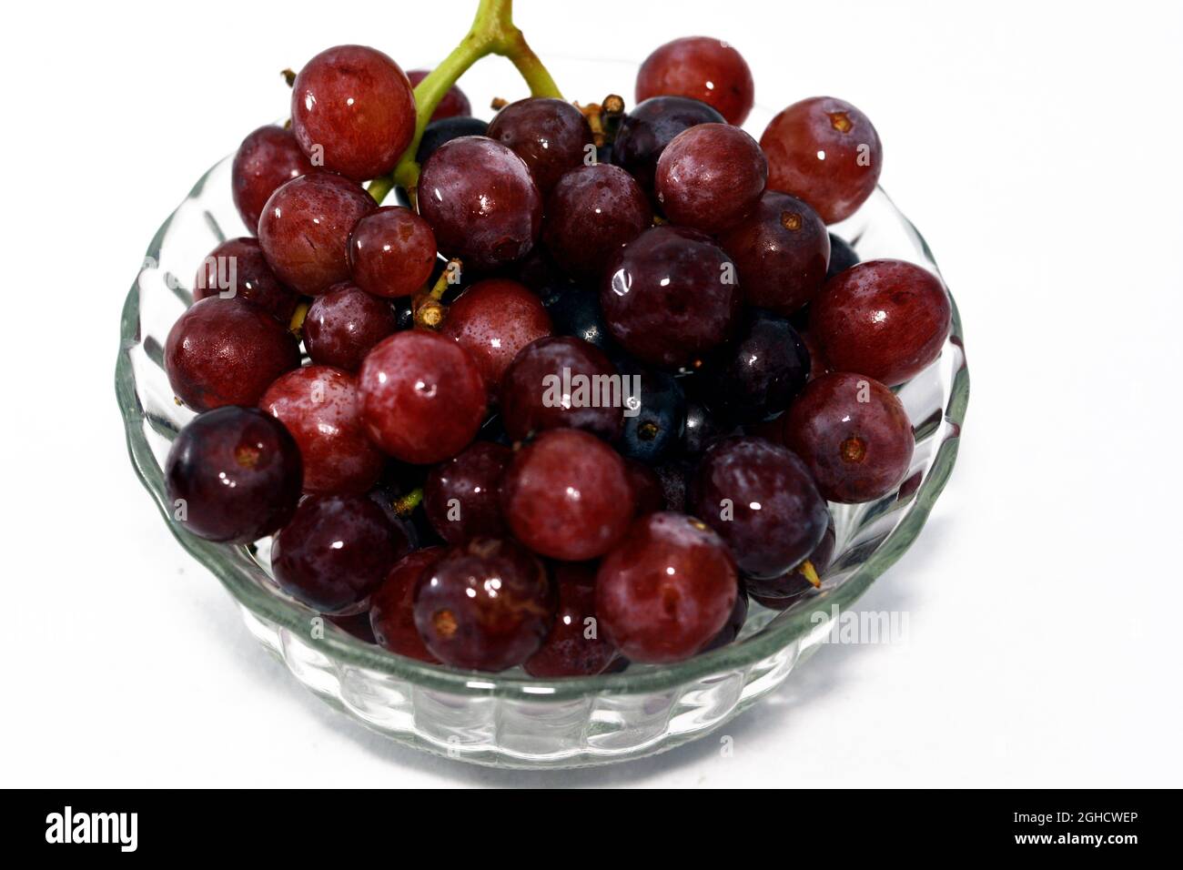 A cluster of an Organic fresh seedless red grapes in a transparent bowl ...