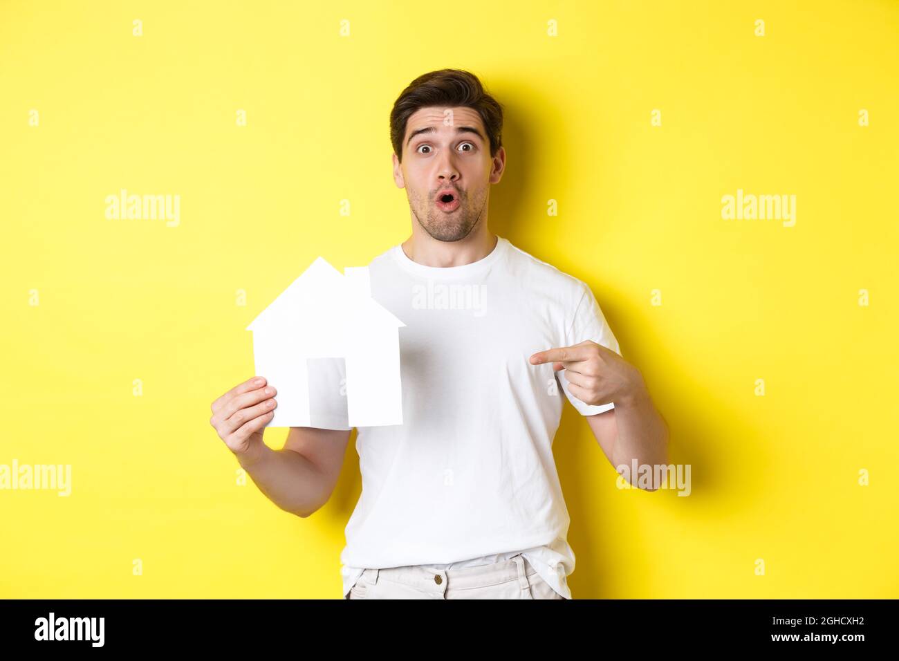 Real estate concept. Excited man pointing finger at paper house model ...