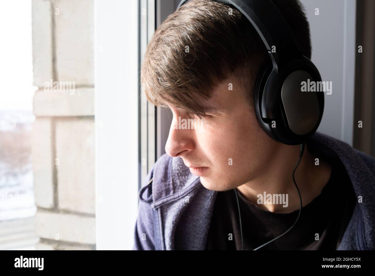 Sad Young Man in Headphones by the Window in the Room Stock Photo - Alamy