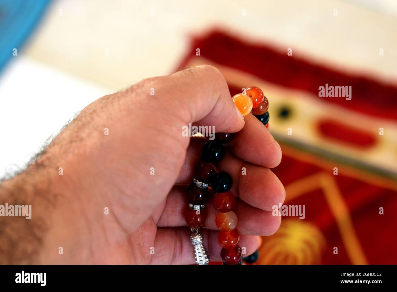 A hand holds an Islamic colorful rosary on a blurred background of a ...