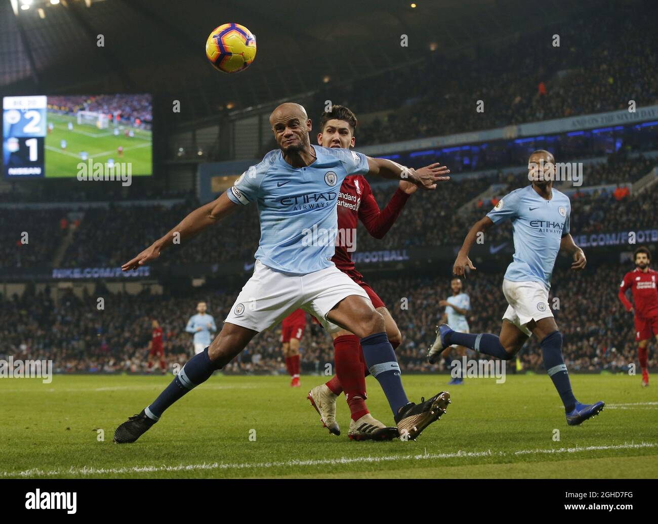 Vincent Kompany of Manchester City holds up Roberto Firmino of ...