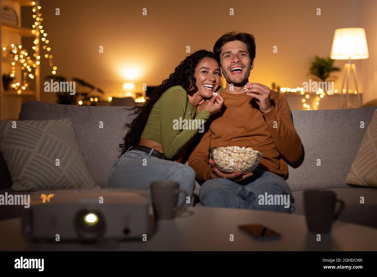 Couple Watching Movie Using Home Cinema Projector Laughing Sitting ...
