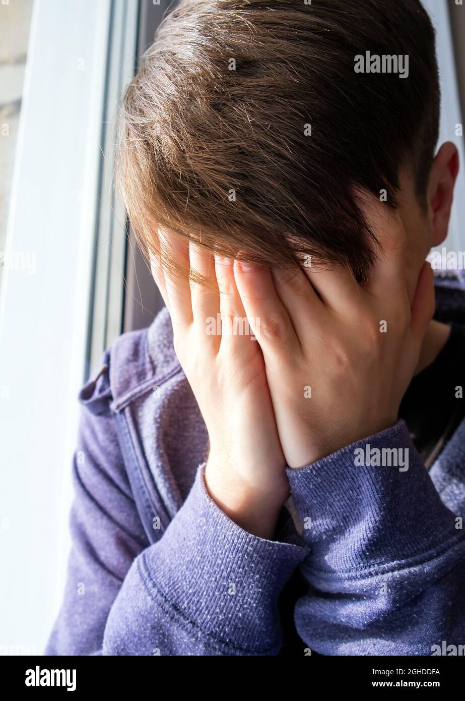 Sad Young Man close his Face with a Hands by the Window in the Room ...