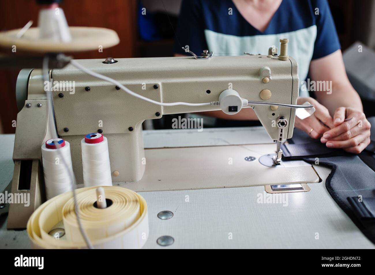 Female hands stitching fabric on professional manufacturing machine at ...