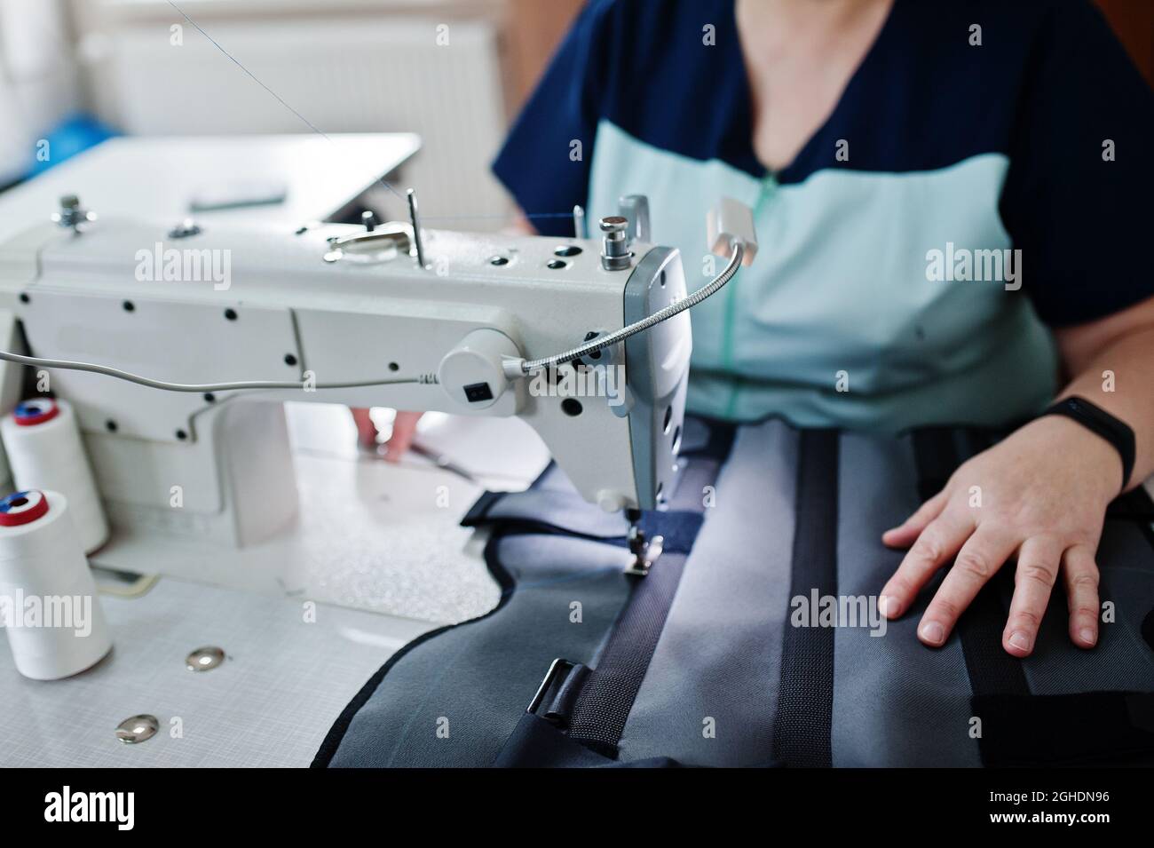 Female hands stitching fabric on professional manufacturing machine at ...