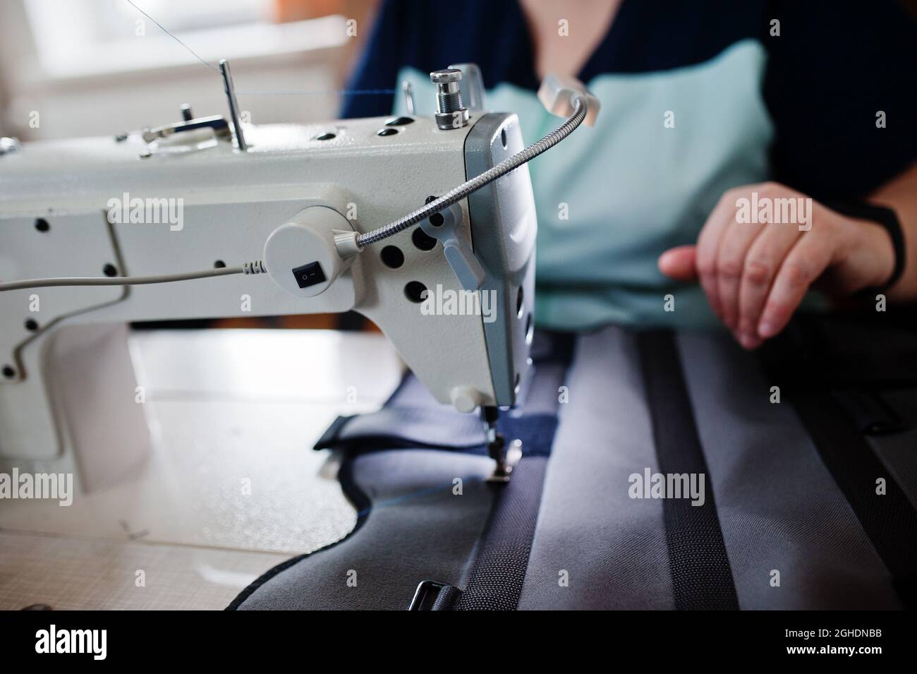 Female hands stitching fabric on professional manufacturing machine at ...