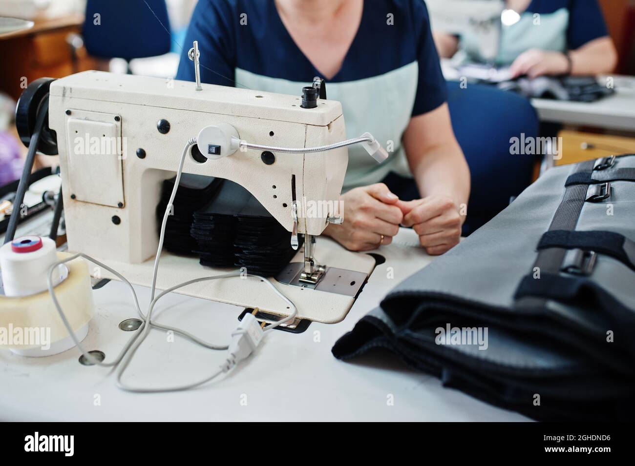 Female hands stitching fabric on professional manufacturing machine at ...