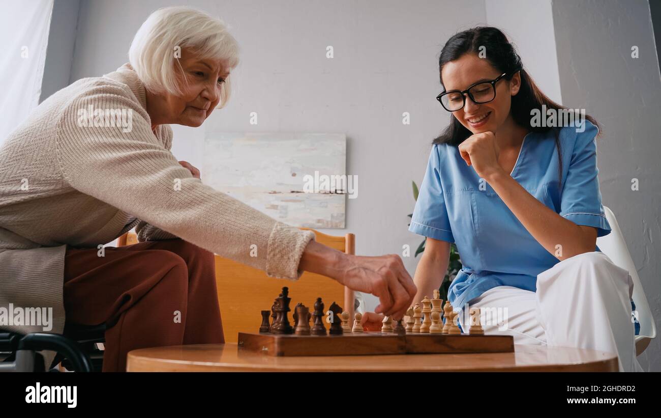 elderly woman and cheerful nurse playing chess in nursing home Stock ...