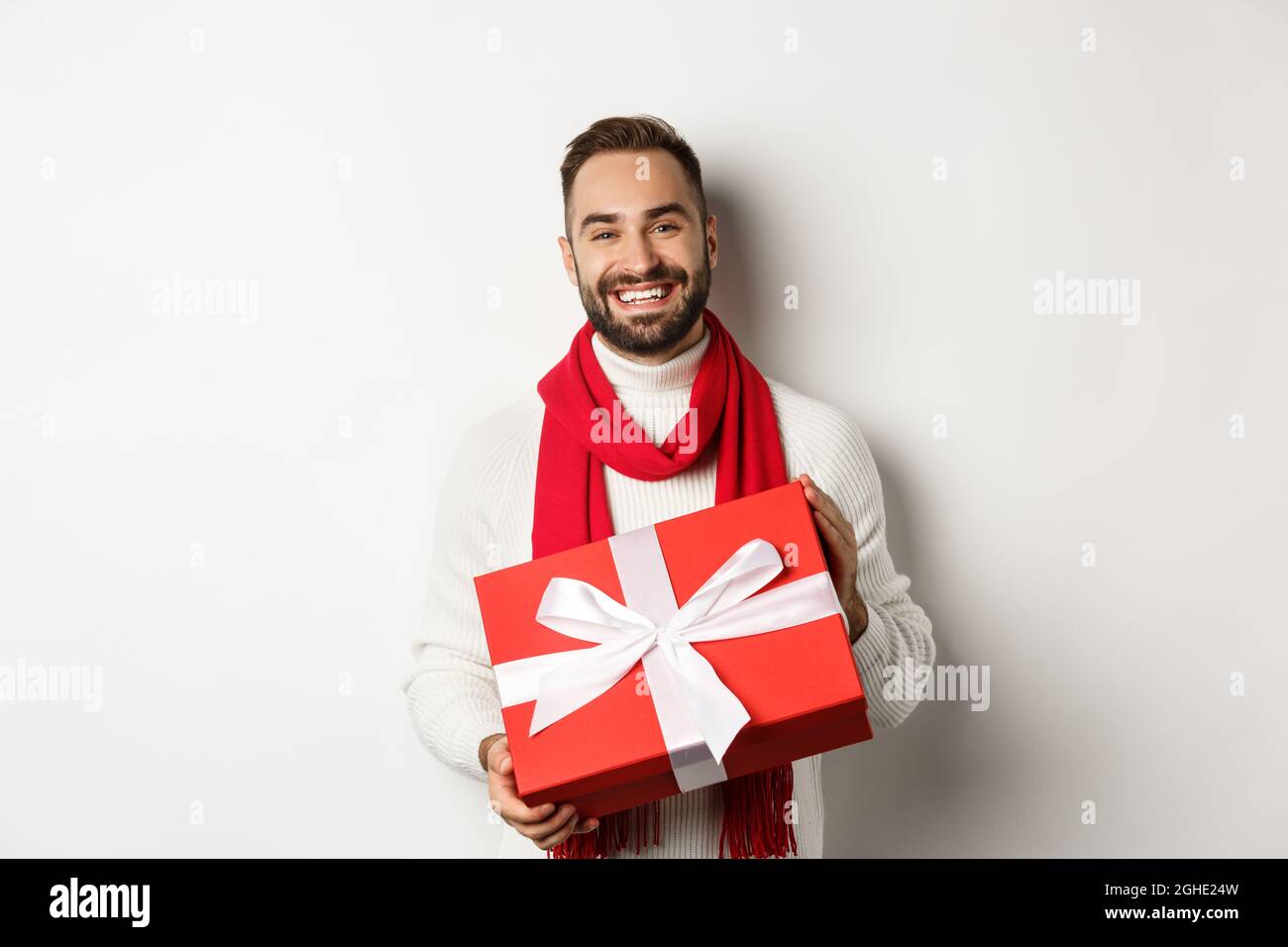 Concept of winter holidays. Smiling man giving you a gift, holding ...