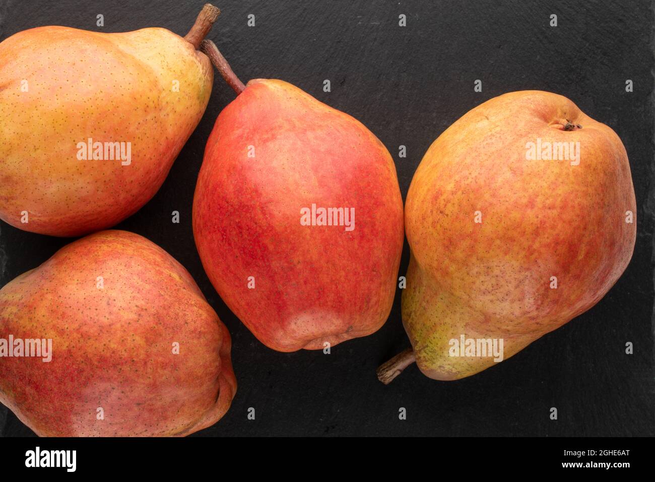 Several natural sweet, red pears on a serving slate board, close-up ...