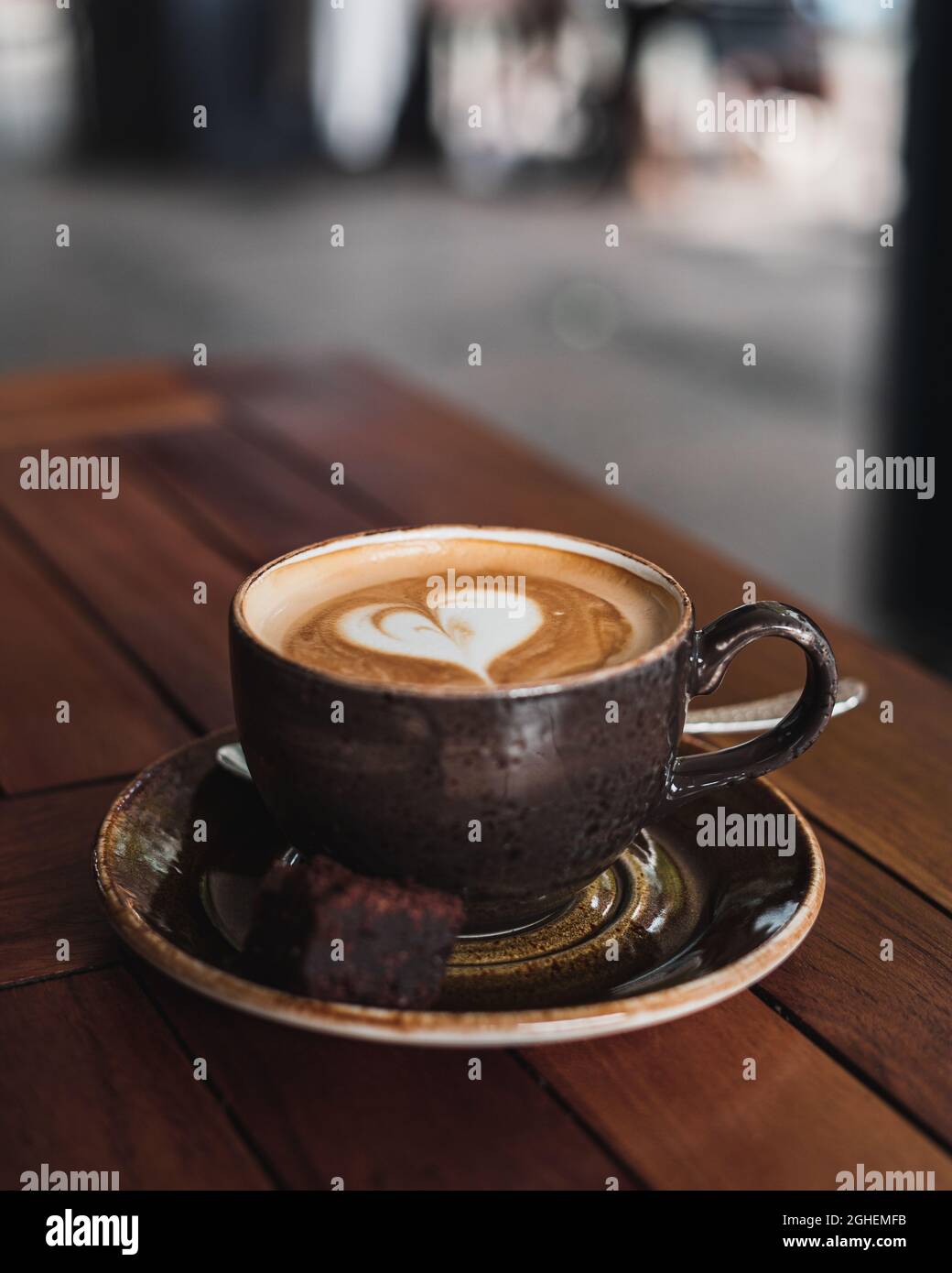Closeup of a cup of fresh hot cappuccino with a piece of sweet pastry ...