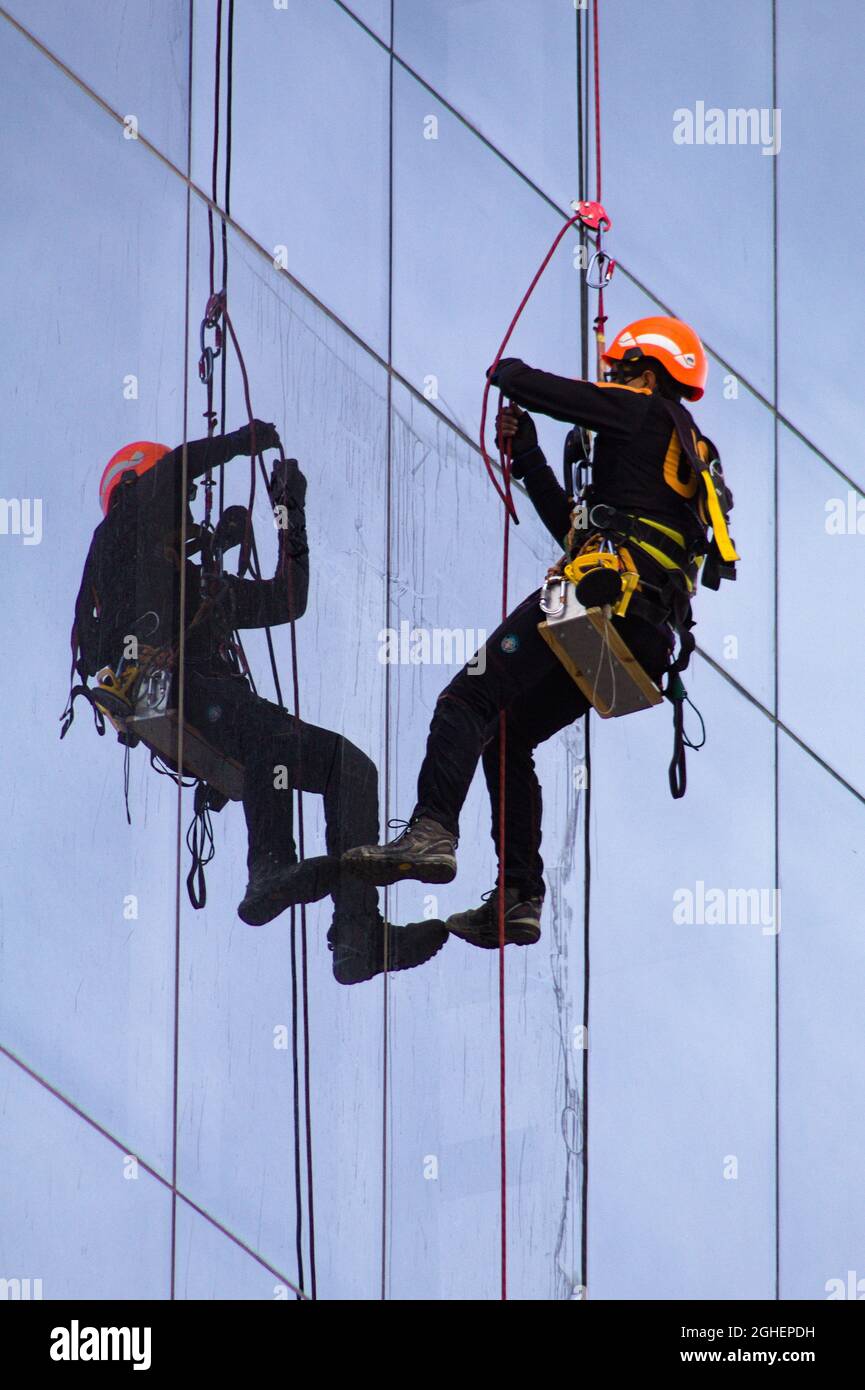 Person climbing on the skyscraper building with glass windows Stock ...