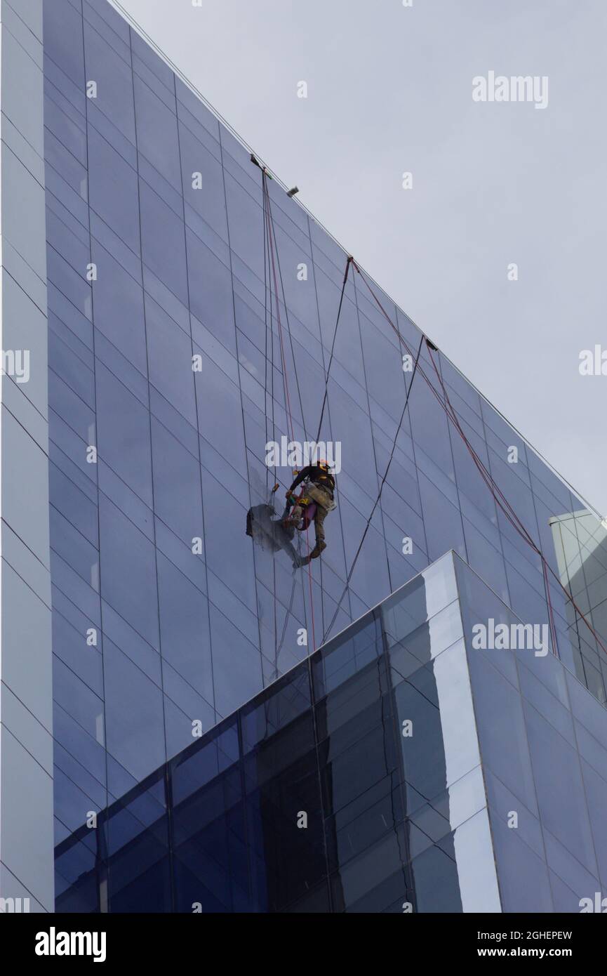 Person climbing on the skyscraper building with glass windows Stock ...