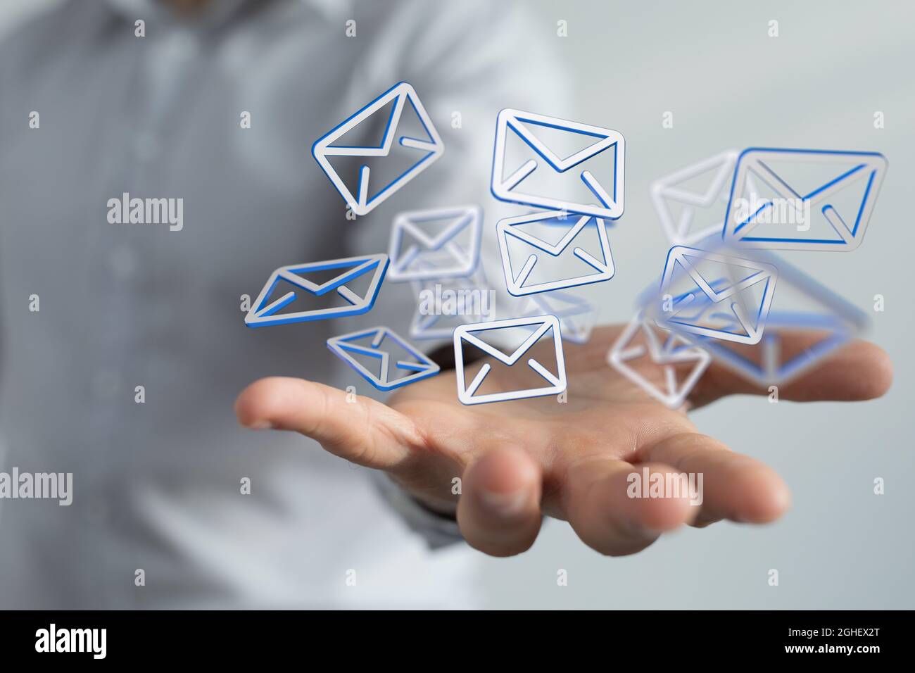 Closeup of a 3D rendered hologram of email icons hovering over a man's ...