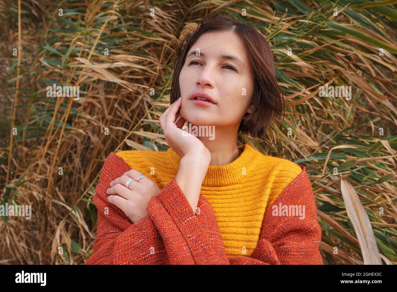 Attractive young woman standing on a windy cold beach wrapped in warm ...