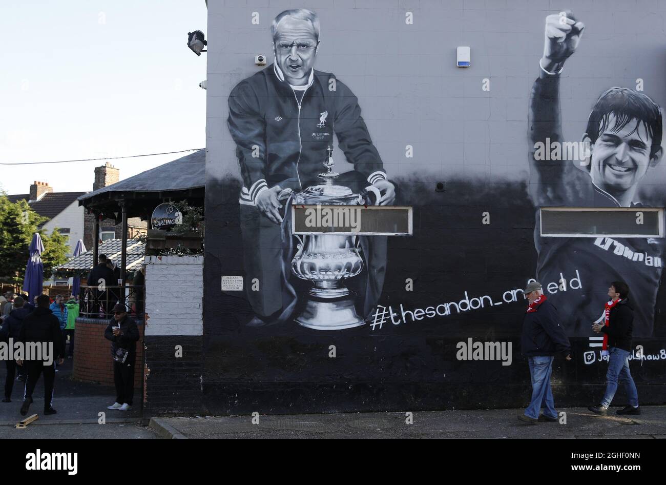 Fans walk past a mural of former Liverpool managers Kenny Dalglish and ...