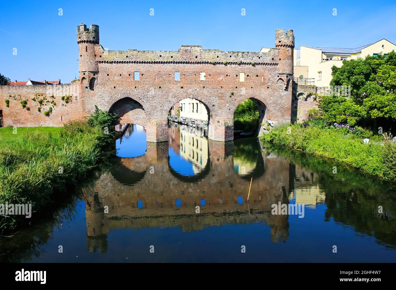 View over water canal on medieval watergate stone wall with 3 arches ...