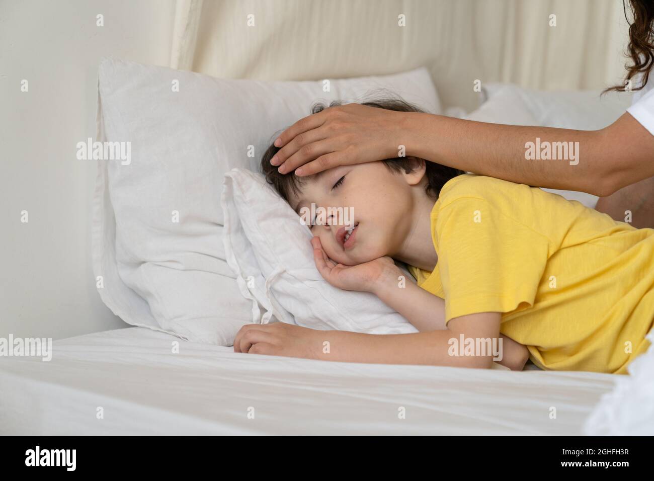 Caring mom check kid temperature touch forehead of peaceful boy ...