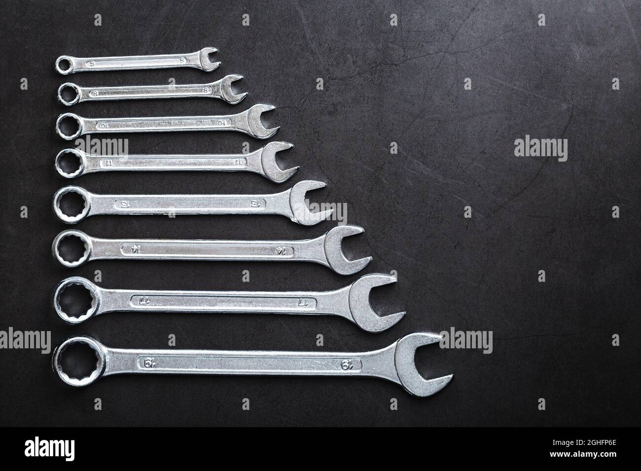A set of wrenches in a row on a black background in a row. Top view ...
