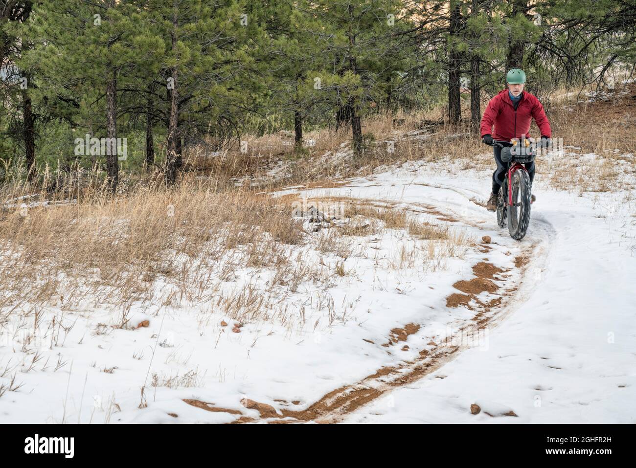 senior male cyclist riding a fat mountain in winter scenery of ...