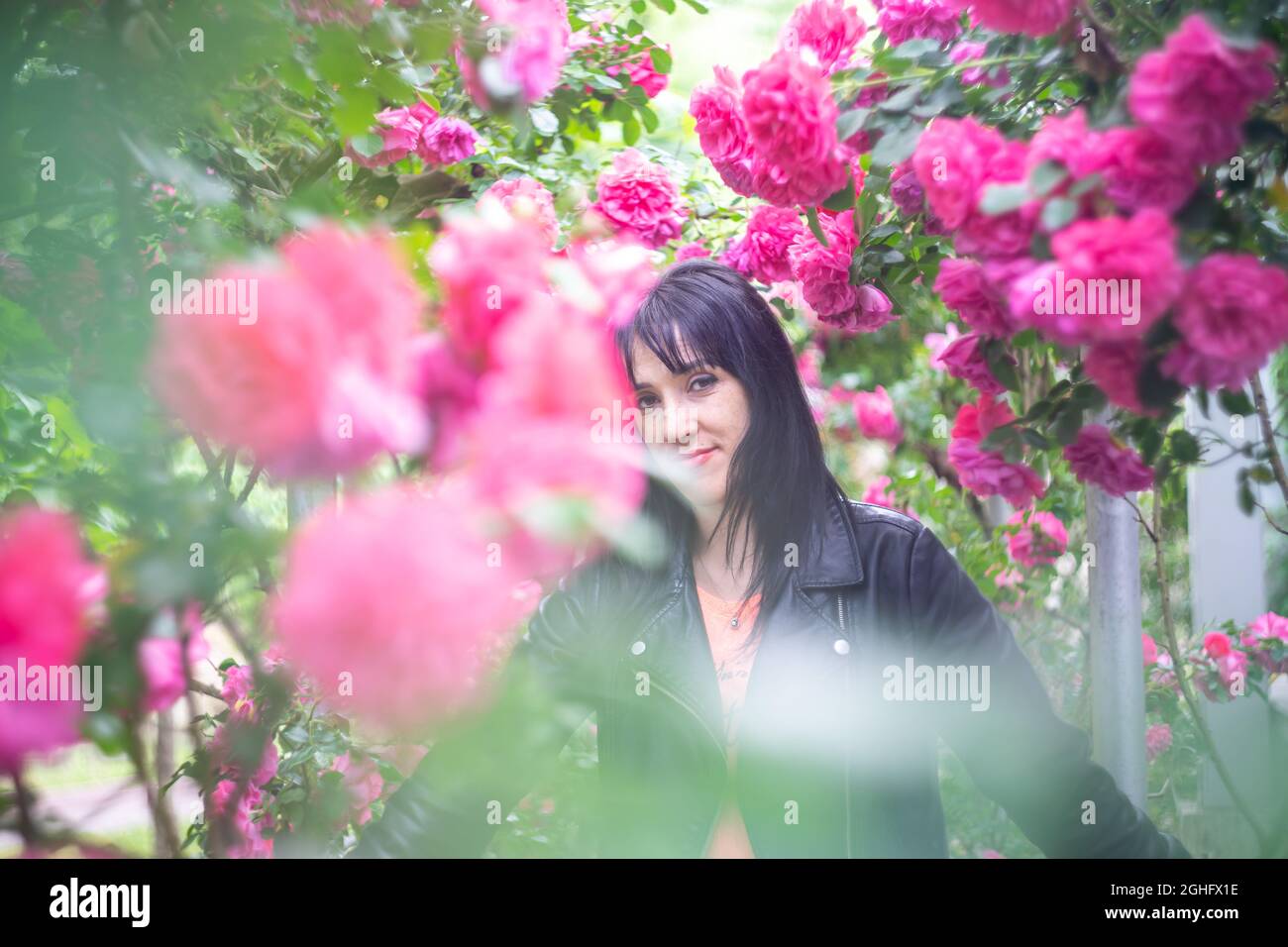 Portrait of a girl sitting between roses Stock Photo - Alamy