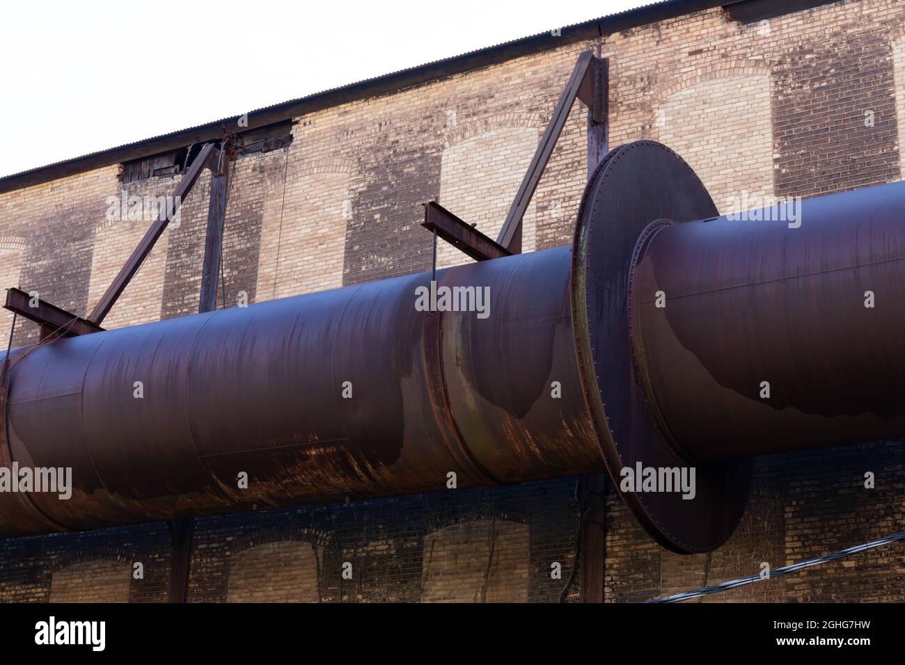 Enormous industrial pipe running along the exterior of a brick ...