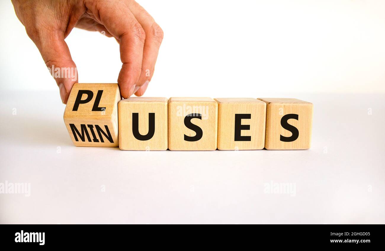 Pluses and minuses symbol. Businessman turns a wooden cube and changes ...