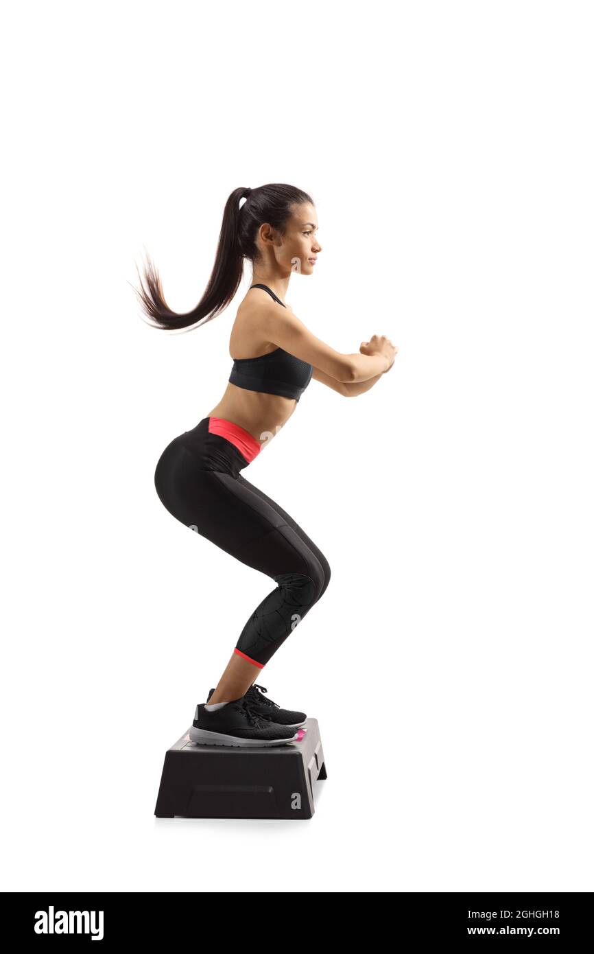 Full length profile shot of a young woman exercising step aerobic ...