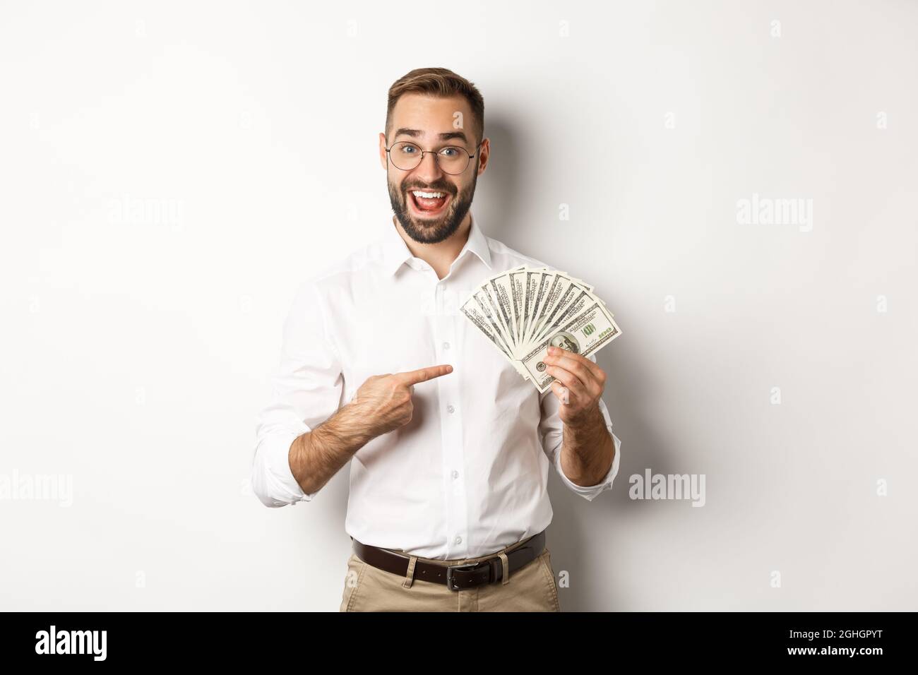 Excited businessman pointing at money, showing dollars and smiling ...