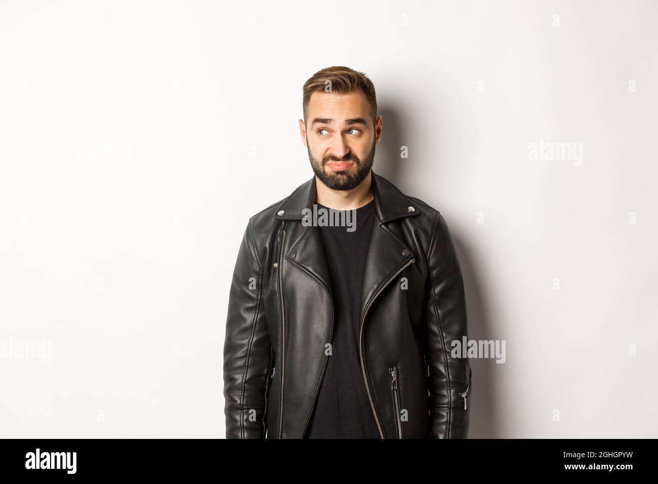 Indecisive gloomy man in black leather jacket, looking left and feeling ...