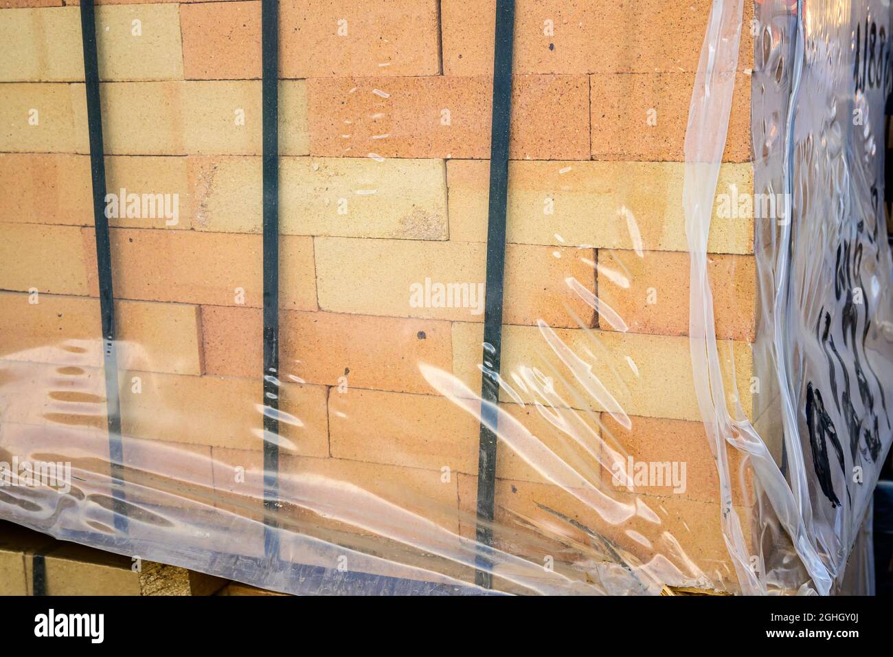 Red brick covered with packaging film on pallets in a warehouse of ...