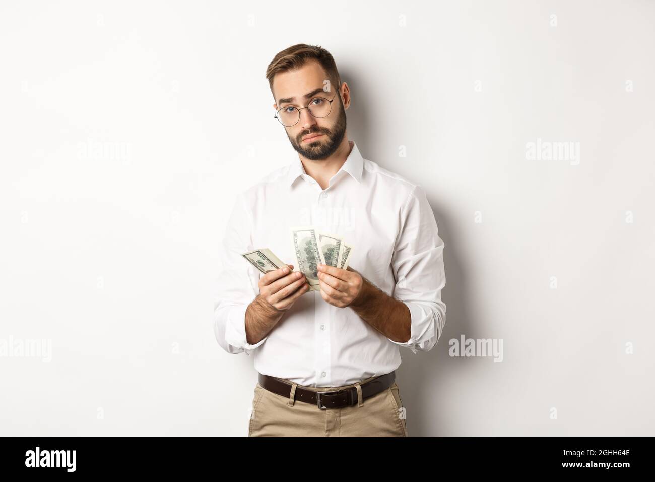 Handsome businessman counting money and looking at camera, standing ...