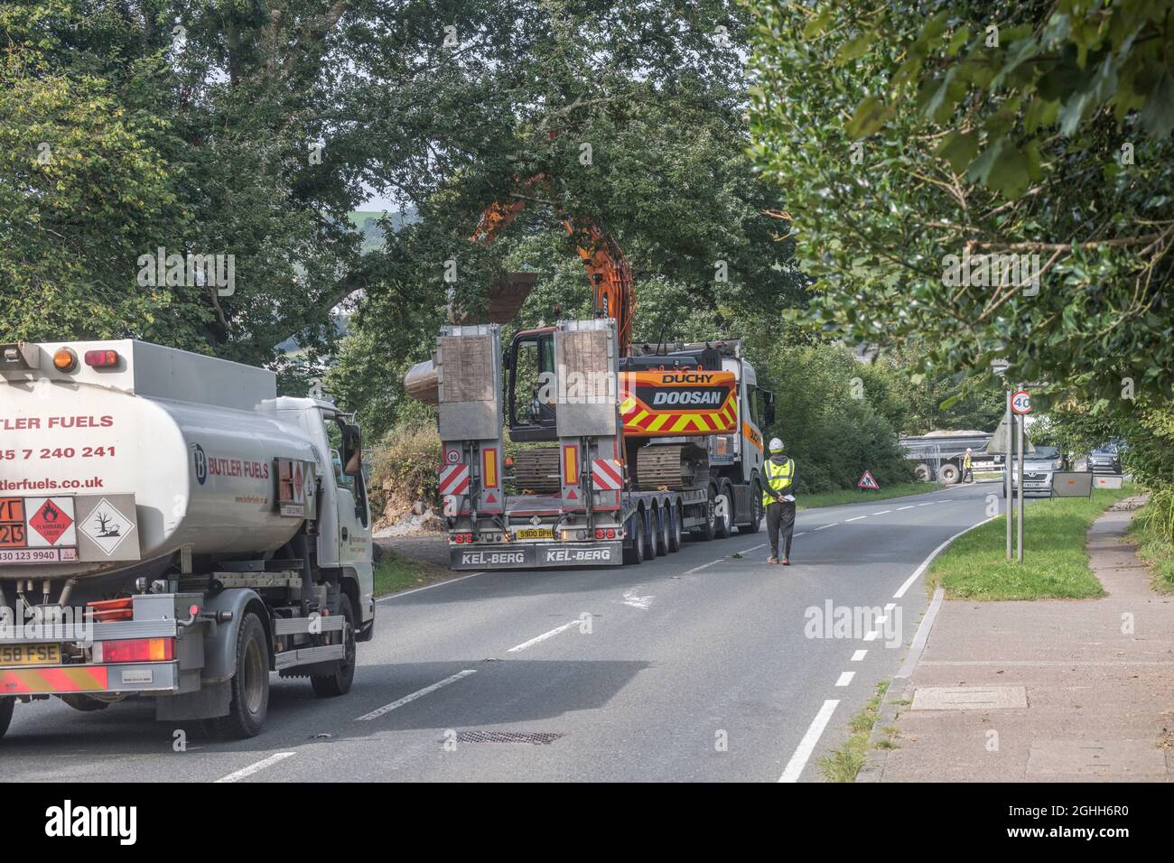 Low loader with construction site excavator being unloaded at a civil ...