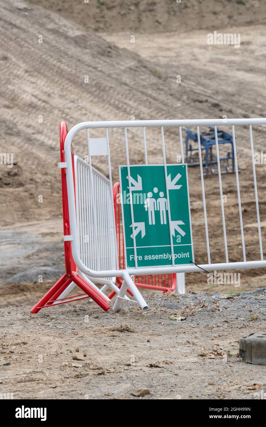 Green fire assembly point sign on construction site barrier fencing ...
