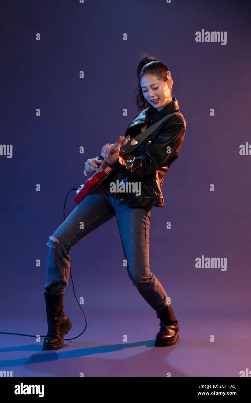 Cheerful young woman playing guitar Stock Photo - Alamy