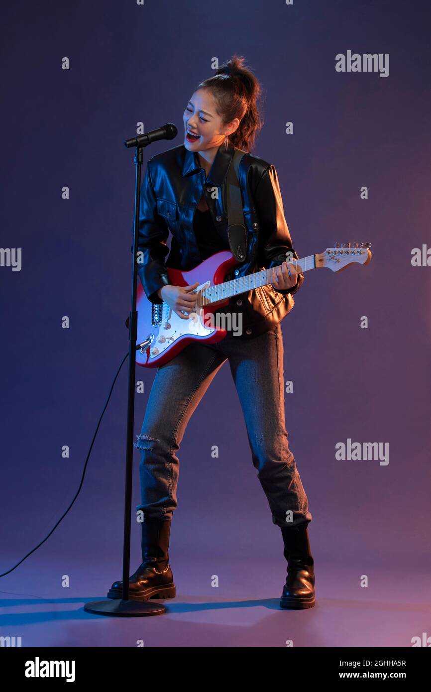 Young woman playing guitar and singing Stock Photo - Alamy