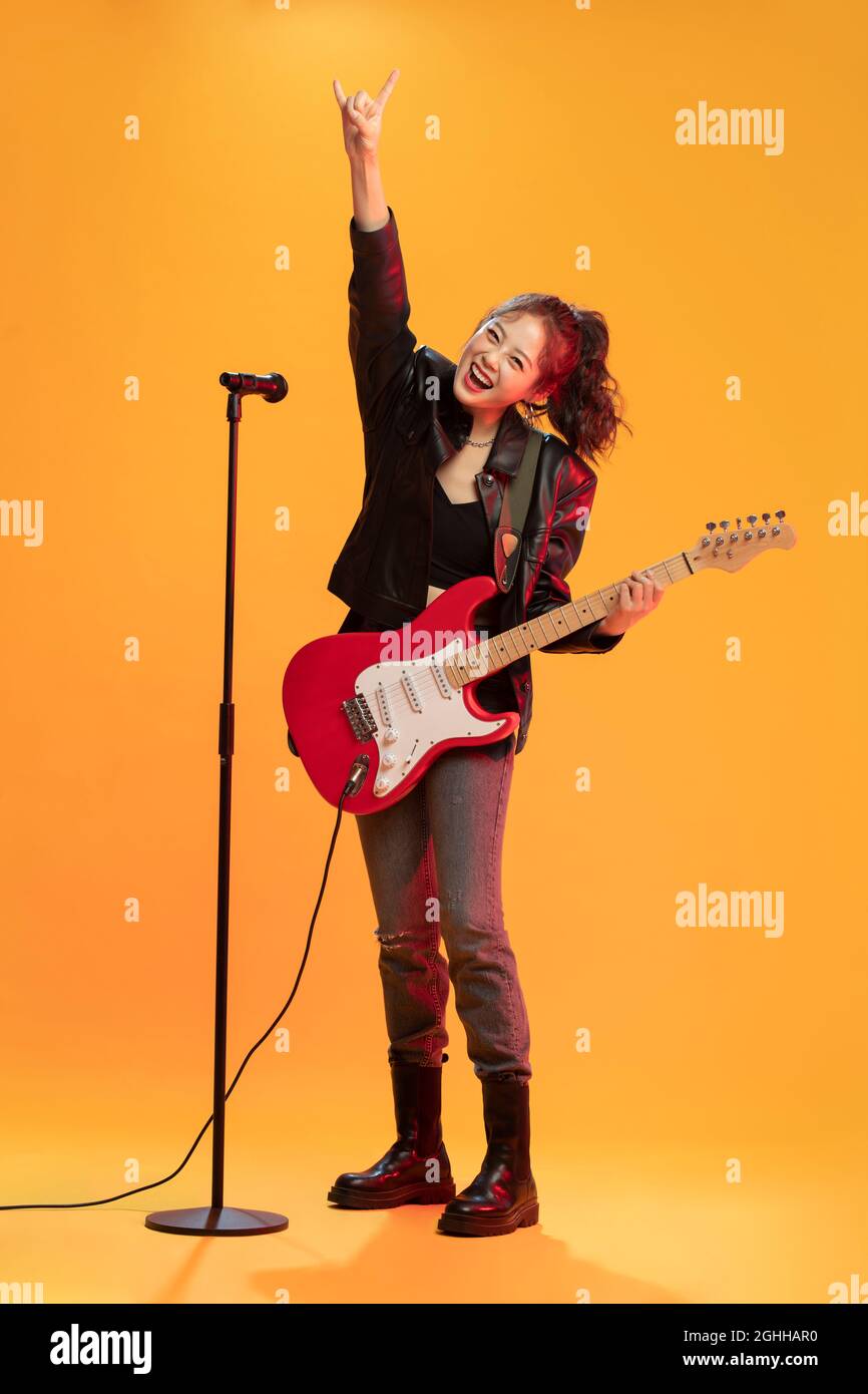 Young woman playing guitar and singing Stock Photo - Alamy