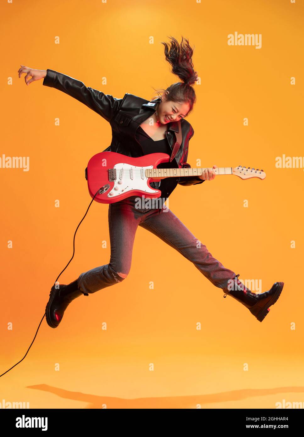Cheerful young woman playing guitar Stock Photo - Alamy