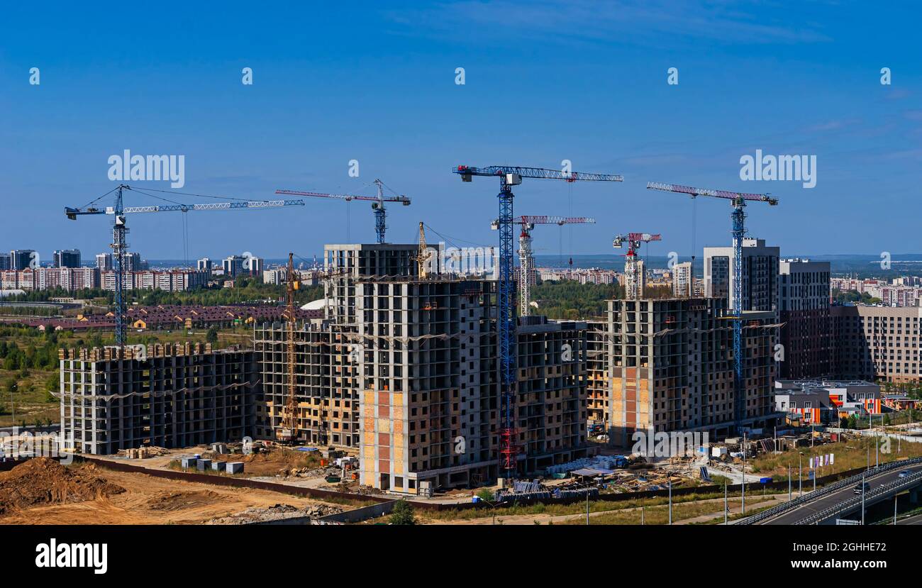 Construction cranes and houses under construction. Construction of a ...