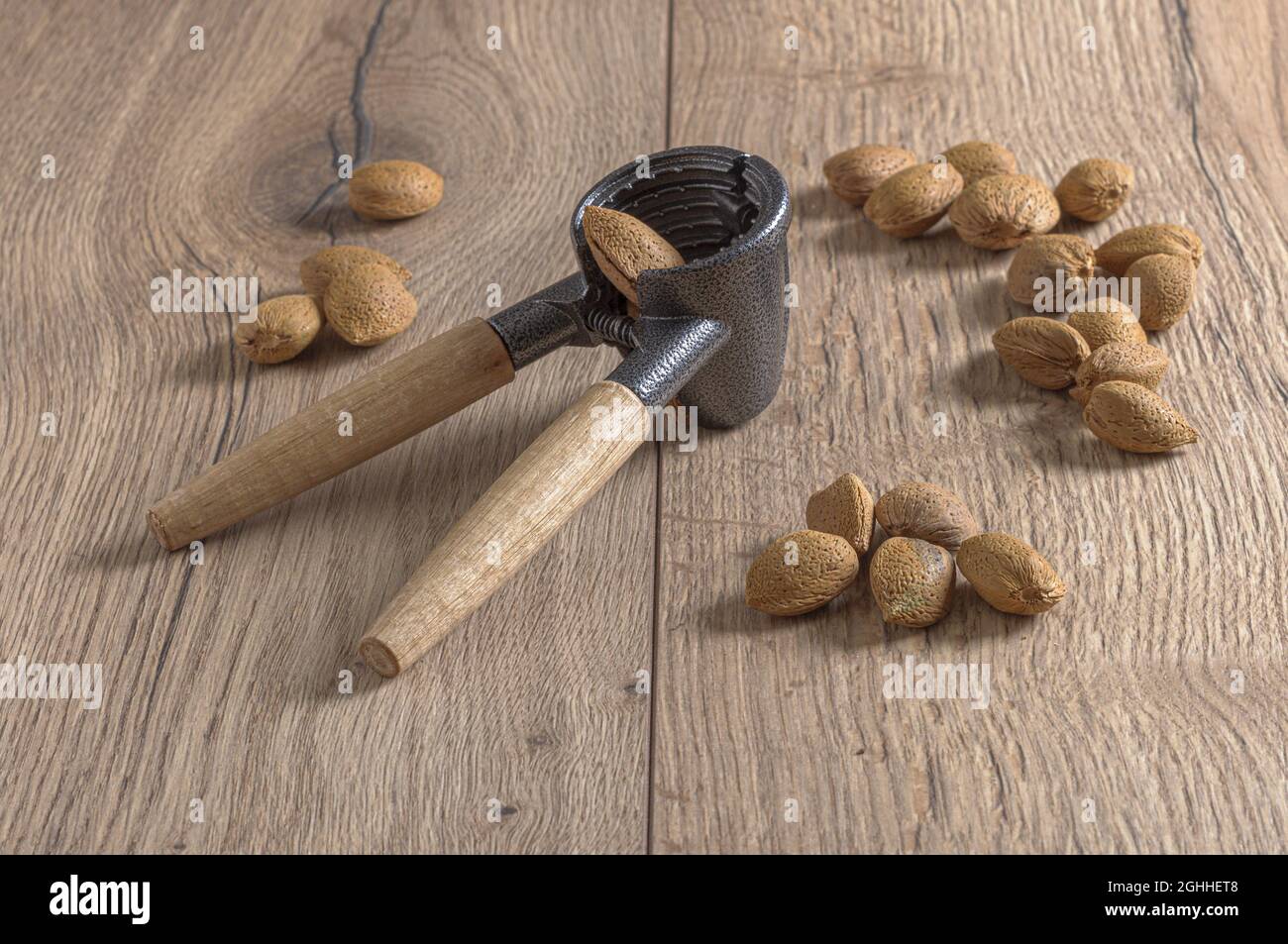 Closeup of a nutcracker and almonds on a wooden surface Stock Photo - Alamy