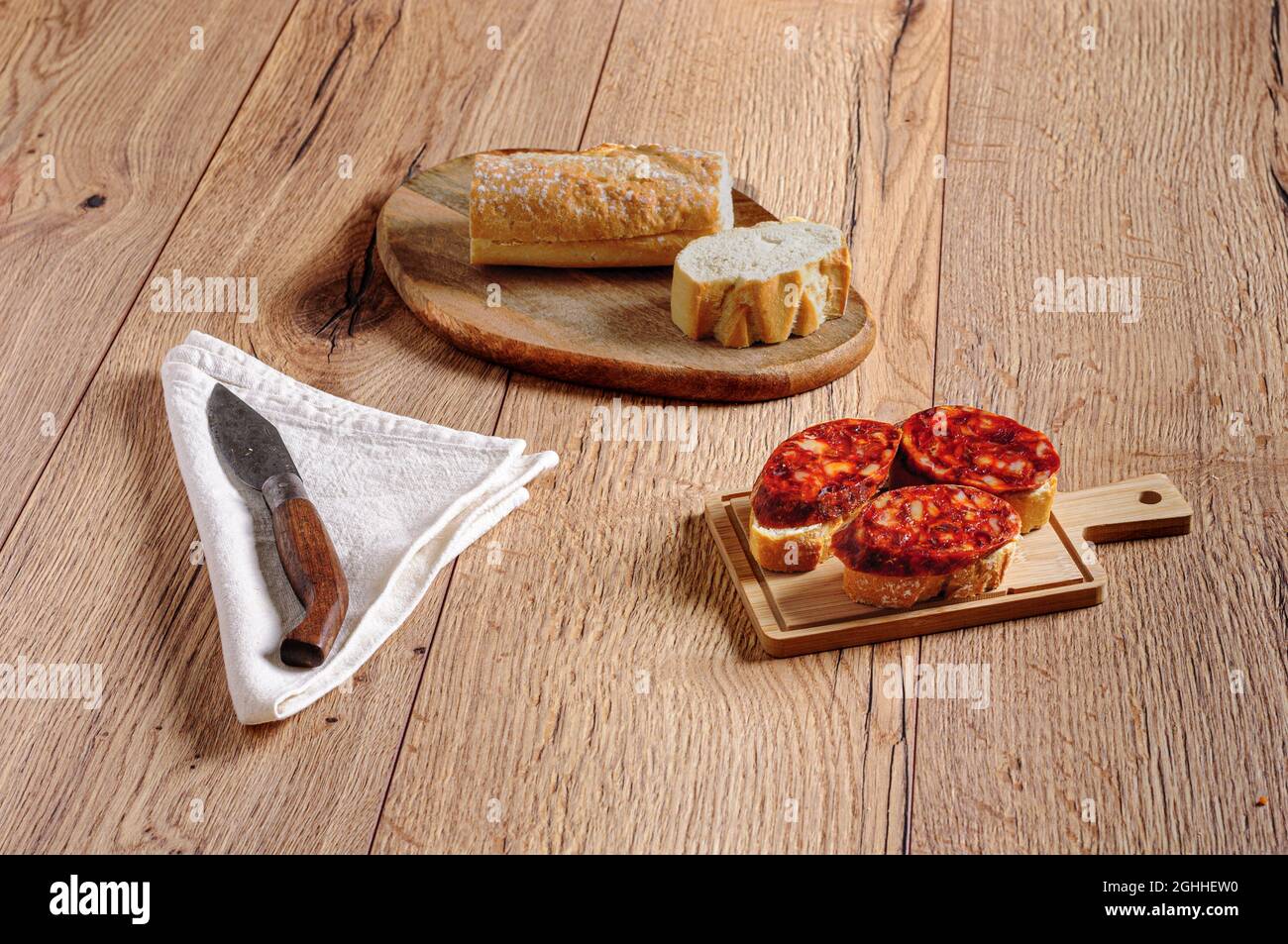 Loaf of bread with sausages and a knife on a wooden surface Stock Photo ...