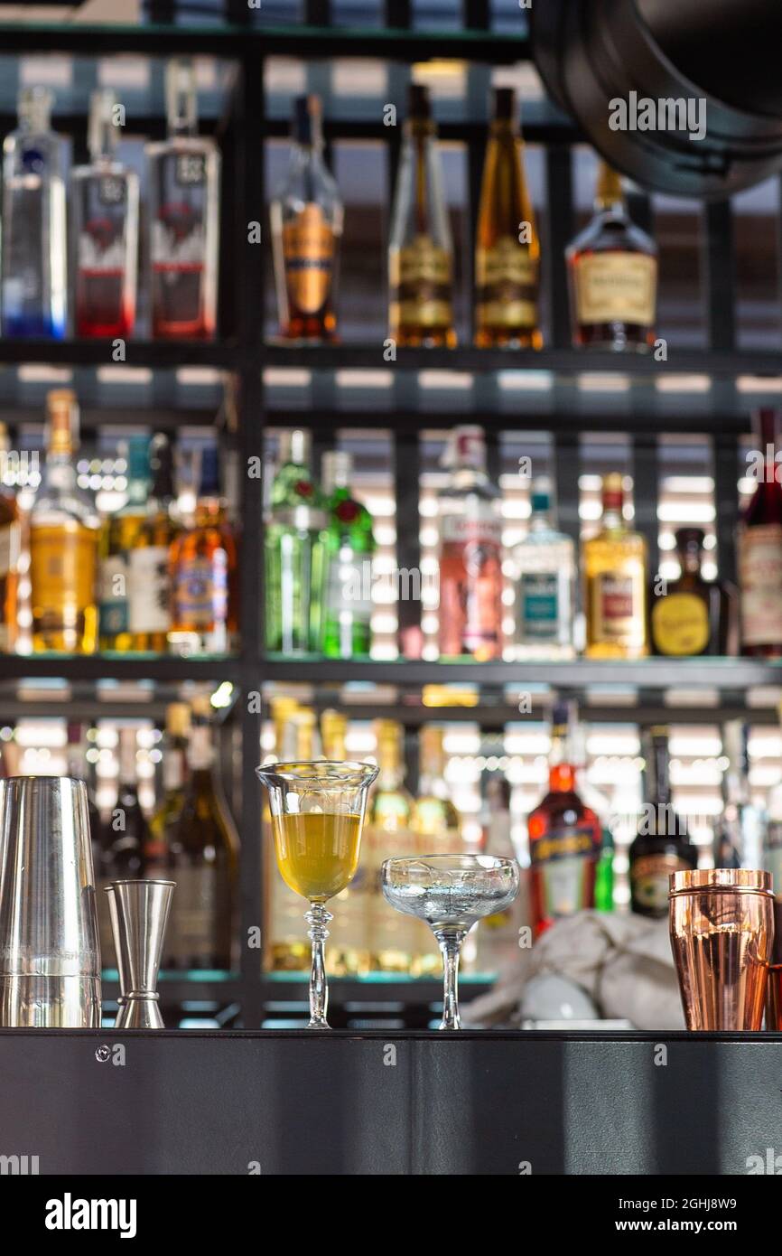 Glass with yellow lemon cocktail on the bar on a blurred bar background ...