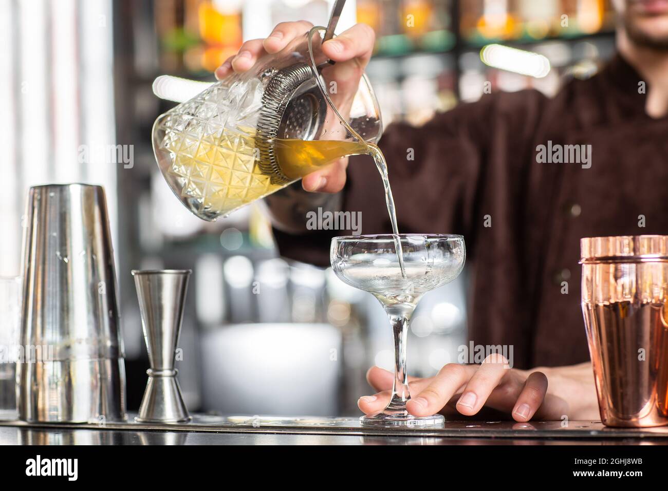 Bartender pouring an alcohol from the measuring glass cup through the ...
