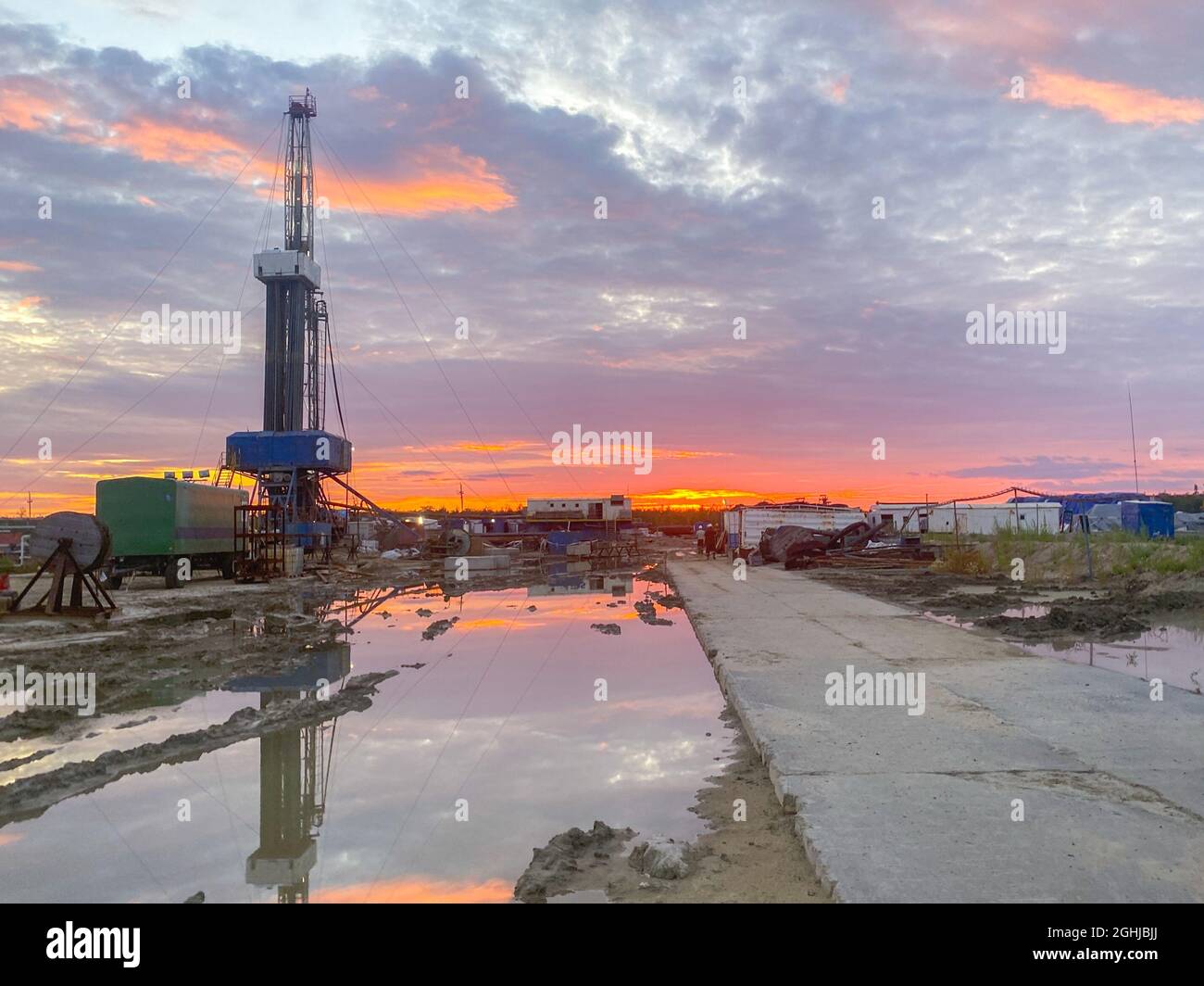 An oil field with an oil rig and wagons. Reflection in a puddle at ...