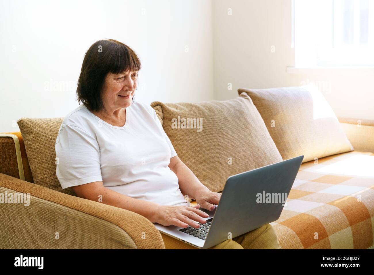 Elderly mature woman using wireless laptop apps browsing internet ...
