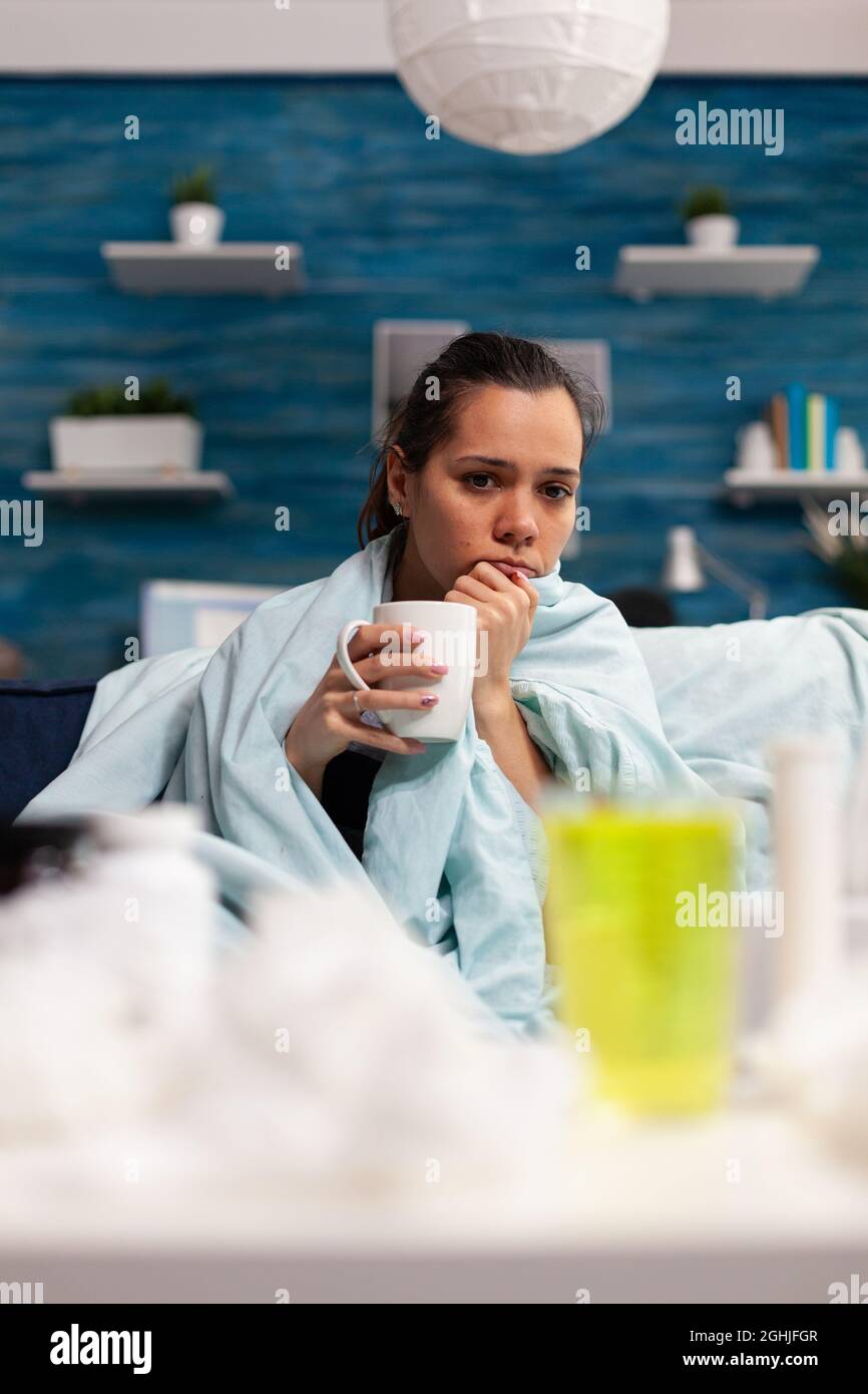 Woman with flu sitting at home drinking hot tea feeling sick. Person ...